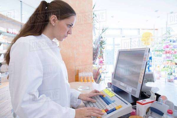 Pharmacist in pharmacy using computer - Royalty-free Stock Photo | Dissolve