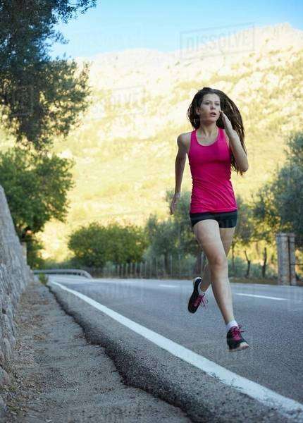 Teenage girl running on road, Majorca, Spain - Stock Photo - Dissolve