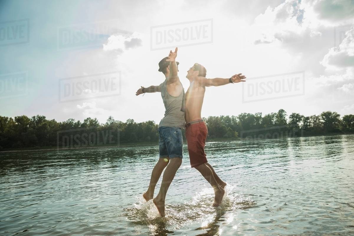 Young men chest bumping in lake - Royalty-free Stock Photo | Dissolve