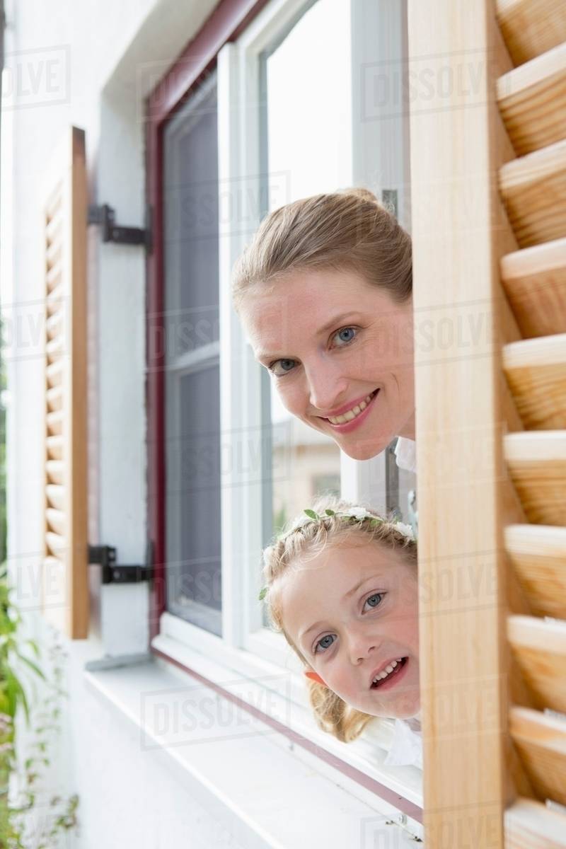 Mother and daughter peering through window - Stock Photo - Dissolve