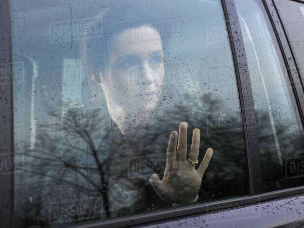 Woman looking through a car's window - Stock Photo - Dissolve