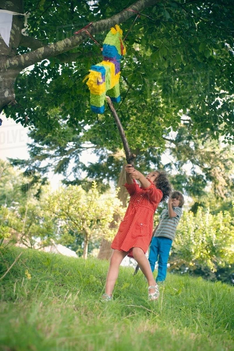 Girl swinging at pinata at party - Stock Photo - Dissolve