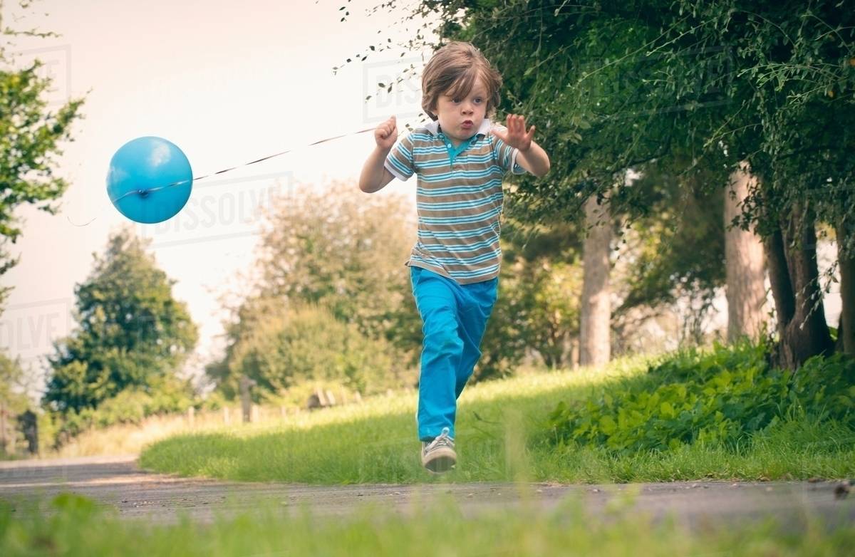 Boy running with balloon outdoors - Royalty-free Stock Photo | Dissolve