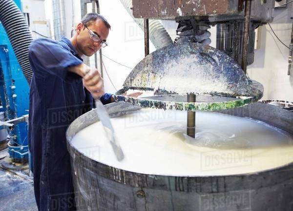 Worker stirring vat of liquid in factory - Stock Photo - Dissolve