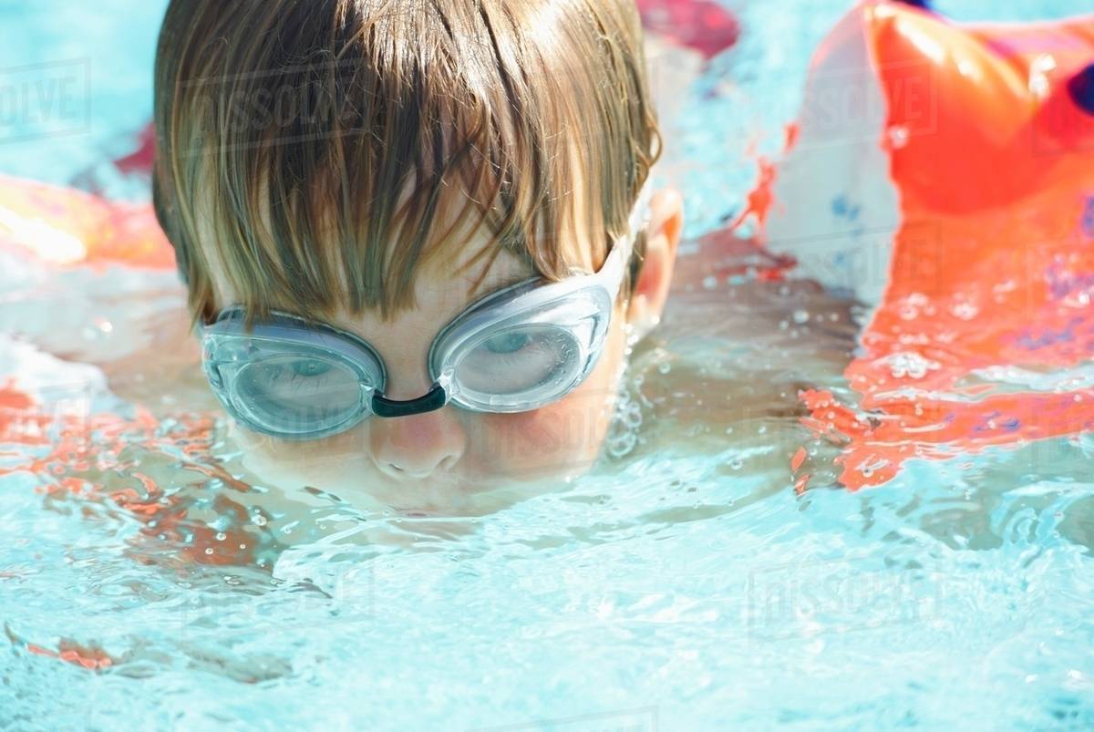 Boy wearing goggles in swimming pool - Stock Photo - Dissolve