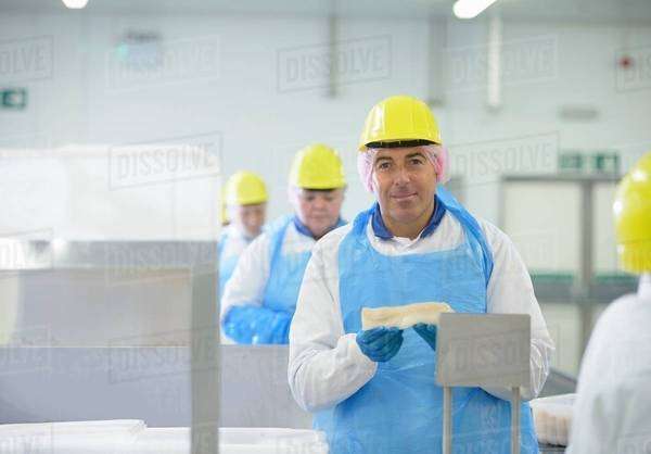 Portrait of worker wearing hard hat on production line in food factory ...