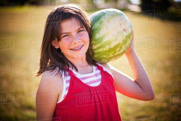Girl carrying watermelon in field - Royalty-free Stock Photo | Dissolve