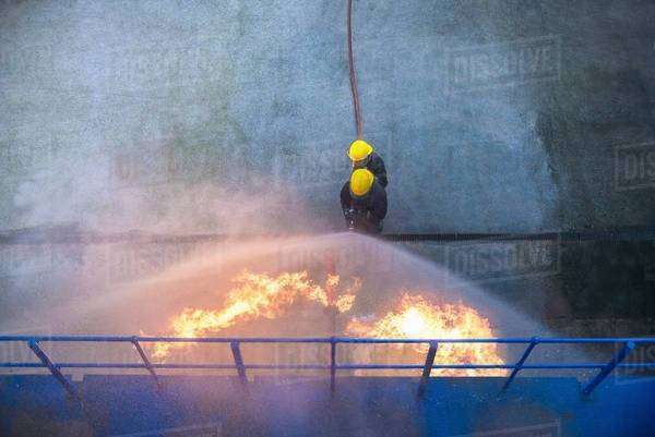 Two firefighters putting out fire in fire simulation training facility ...