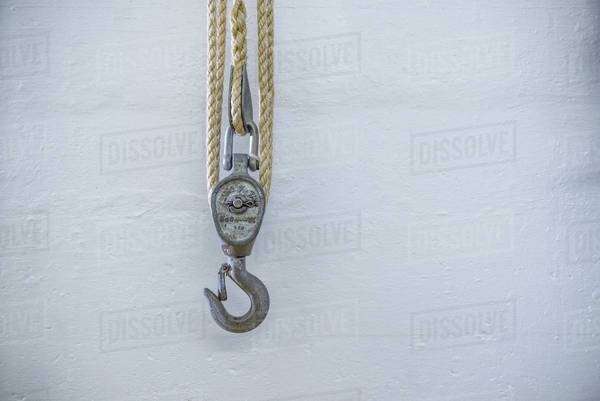 Rope and hook of a block and tackle against white wall in nautical ...