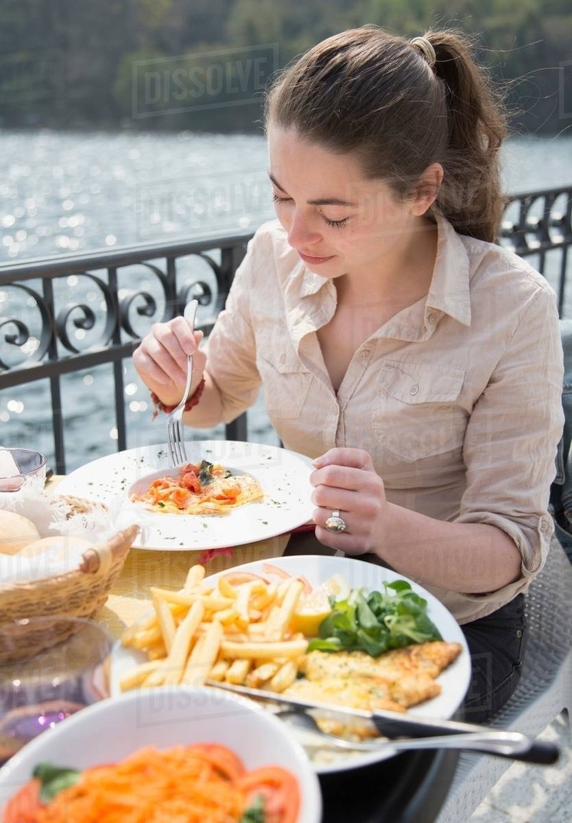 Young woman eating lunch at lakeside restaurant, Lake Mergozzo ...