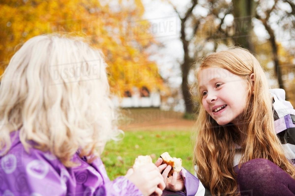 Girls eating together outdoors - Stock Photo - Dissolve
