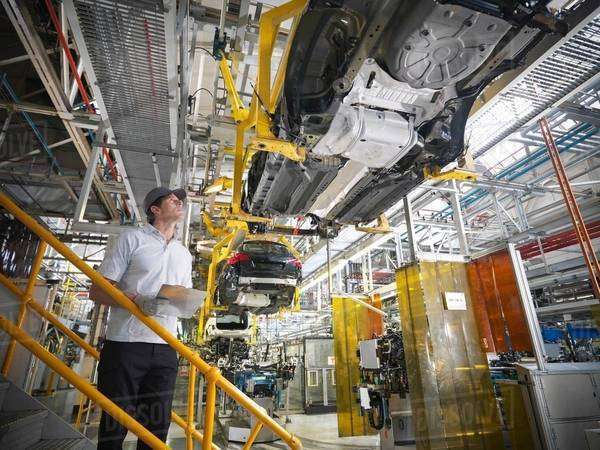 Worker inspecting underneath car body in car factory - Stock Photo ...
