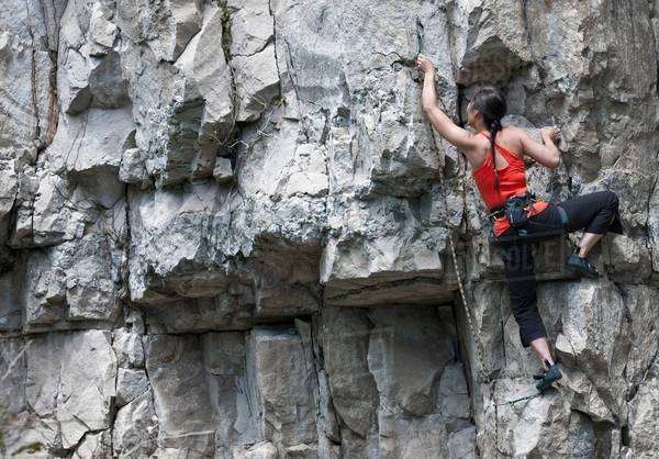 Climber scaling steep cliff face - Stock Photo - Dissolve