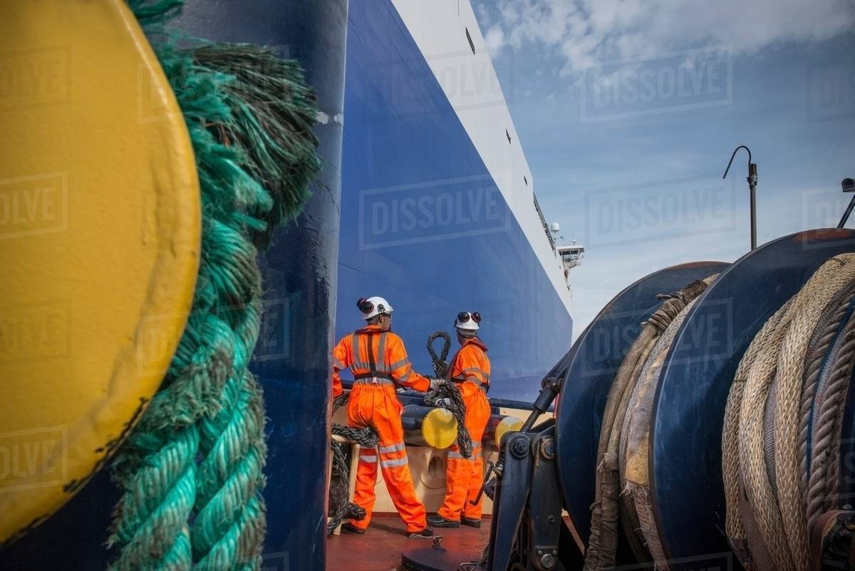 Tug workers on tug at sea with ropes in foreground - Stock Photo - Dissolve