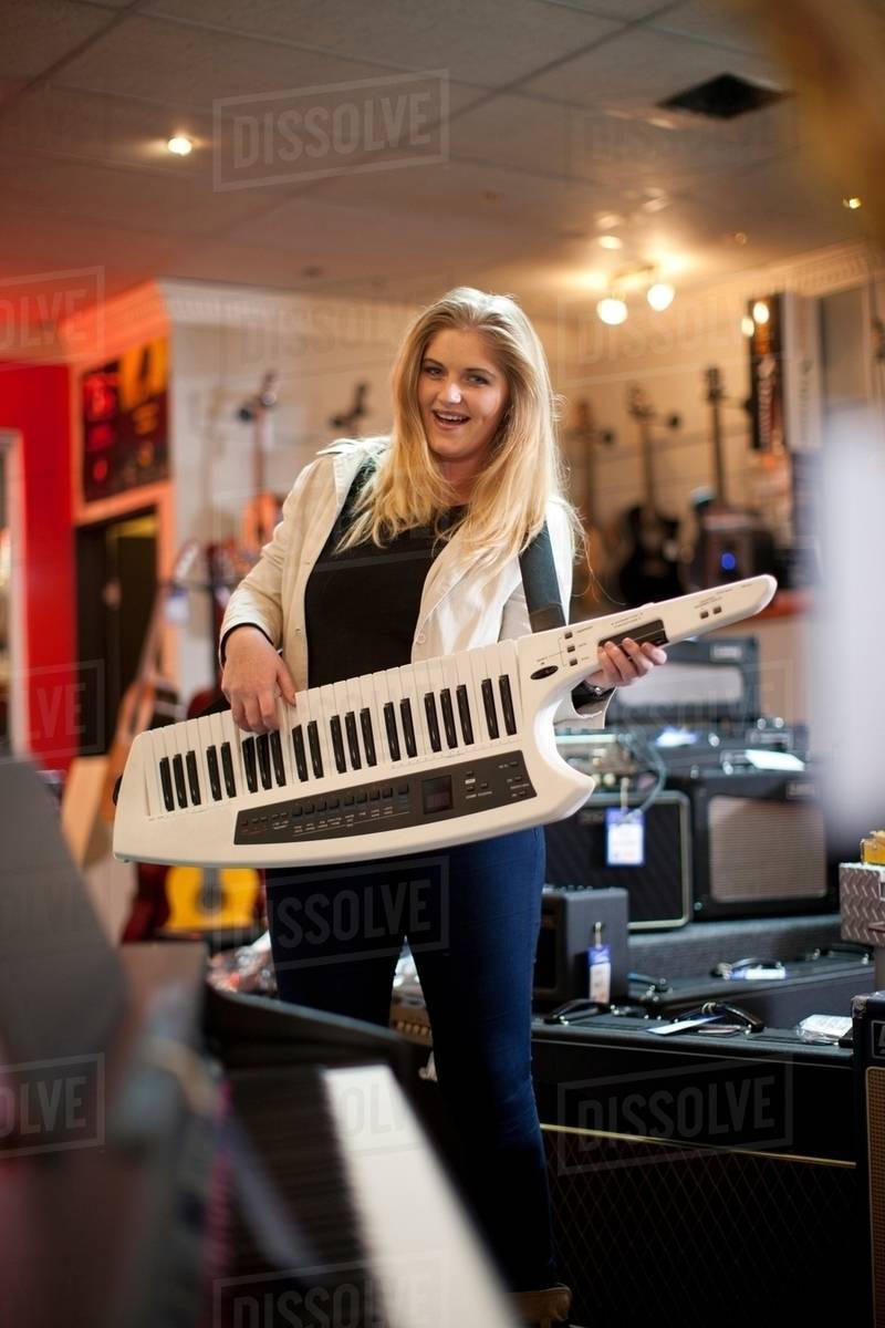 Young woman playing keytar in music store - Royalty-free Stock Photo ...