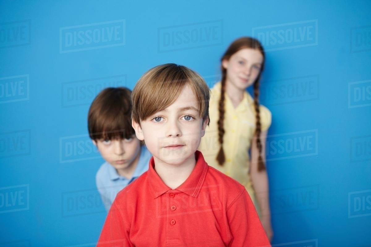 Portrait of three children looking at camera, blue background - Stock ...