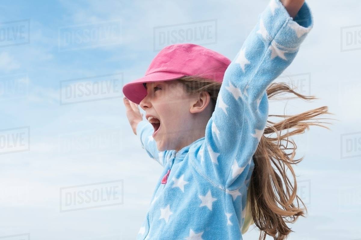 Girl wearing pink cap with arms raised in wind - Royalty-free Stock ...