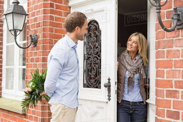 Mid adult couple, woman opening front door - Royalty-free Stock Photo ...