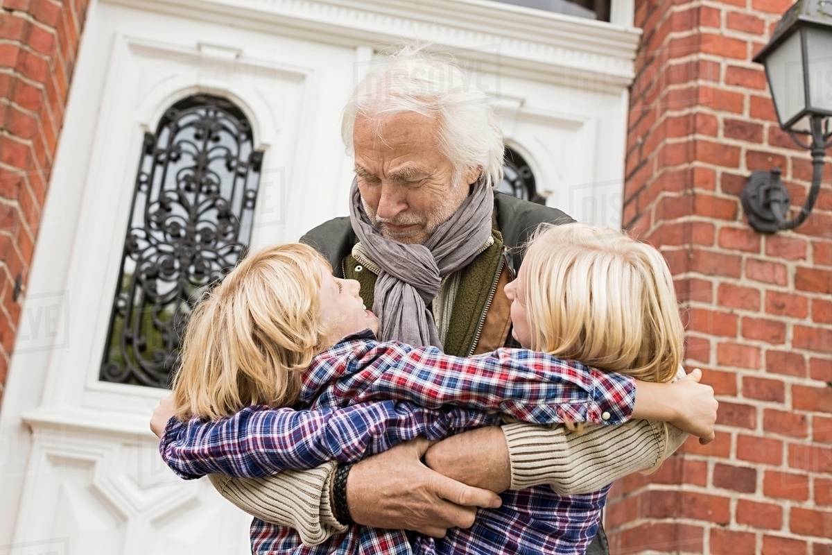 Grandfather hugging grandchildren by front door - Royalty-free Stock ...