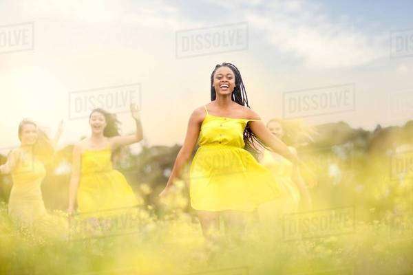 Girls in yellow dancing on meadow - Royalty-free Stock Photo | Dissolve