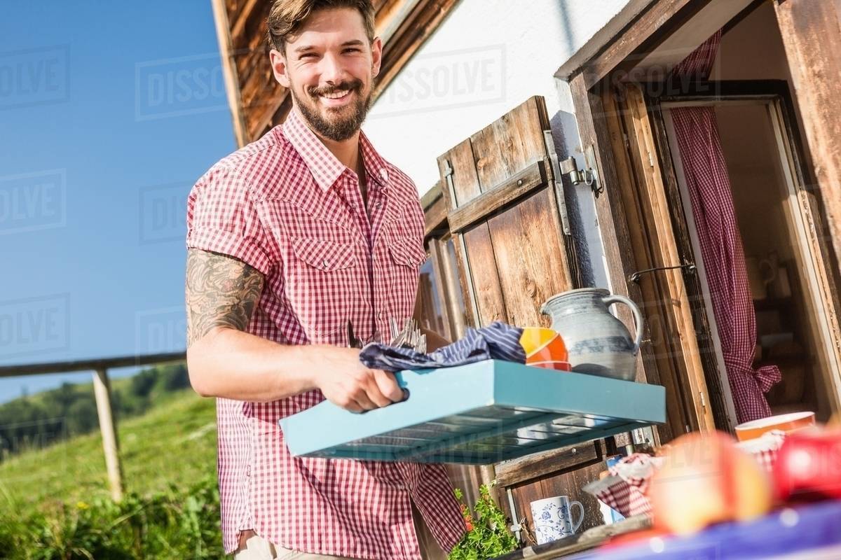 Young man carrying tray outside chalet, Tyrol, Austria - Stock Photo ...