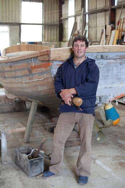 Portrait of mature man holding chisel in boat workshop - Royalty-free ...