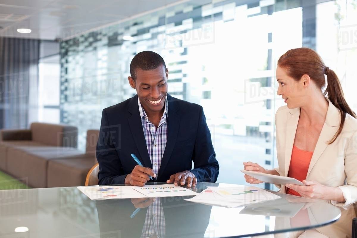 Businesspeople sitting at desk, looking at paperwork - Royalty-free ...