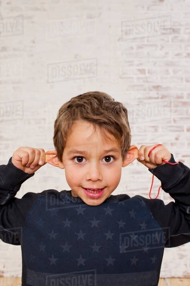 Studio portrait of boy pulling his ears - Stock Photo - Dissolve
