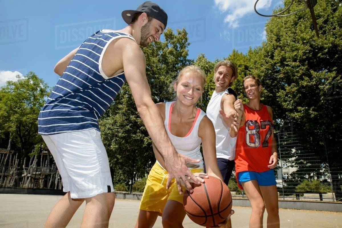 Group of friends playing basketball in park - Stock Photo - Dissolve
