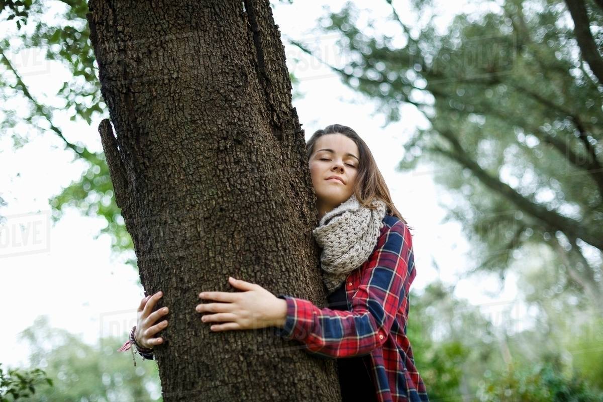 Teenage girl hugging tree in forest - Stock Photo - Dissolve