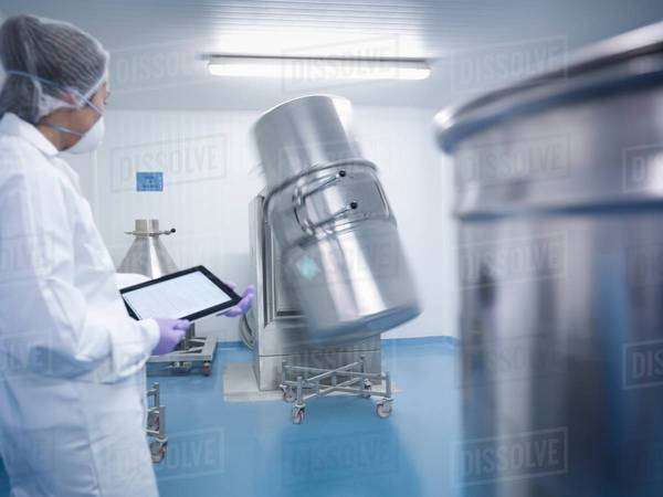 Worker holding digital tablet and watching ingredient mixing machine in ...