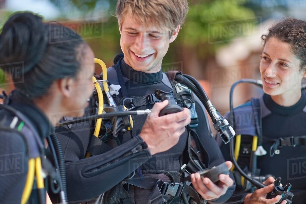 Scuba diving instructor demonstrating oxygen mask to female pupils ...