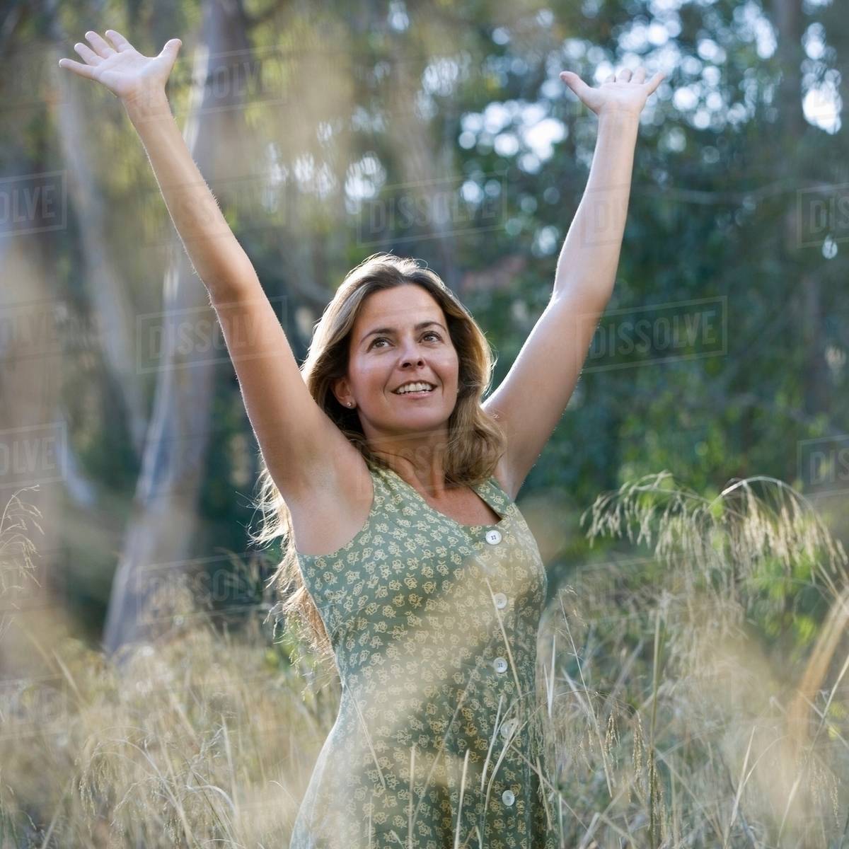 Smiling woman raising arms overhead - Stock Photo - Dissolve