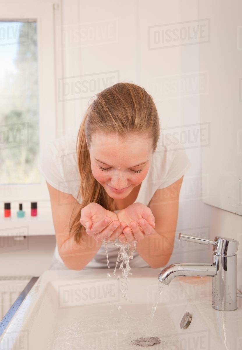 Teenage girl washing face in bathroom - Stock Photo - Dissolve