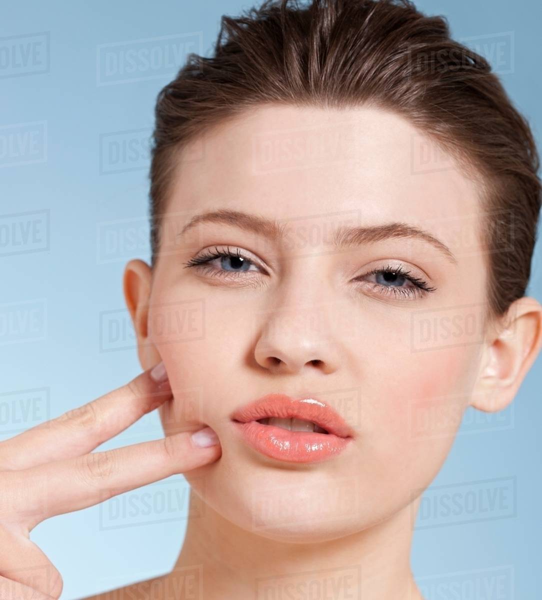 Close up of woman touching her cheeks - Royalty-free Stock Photo | Dissolve