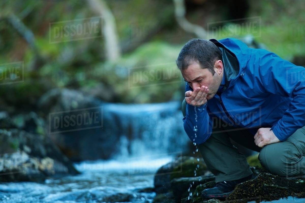 Man drinking water from stream - Royalty-free Stock Photo | Dissolve