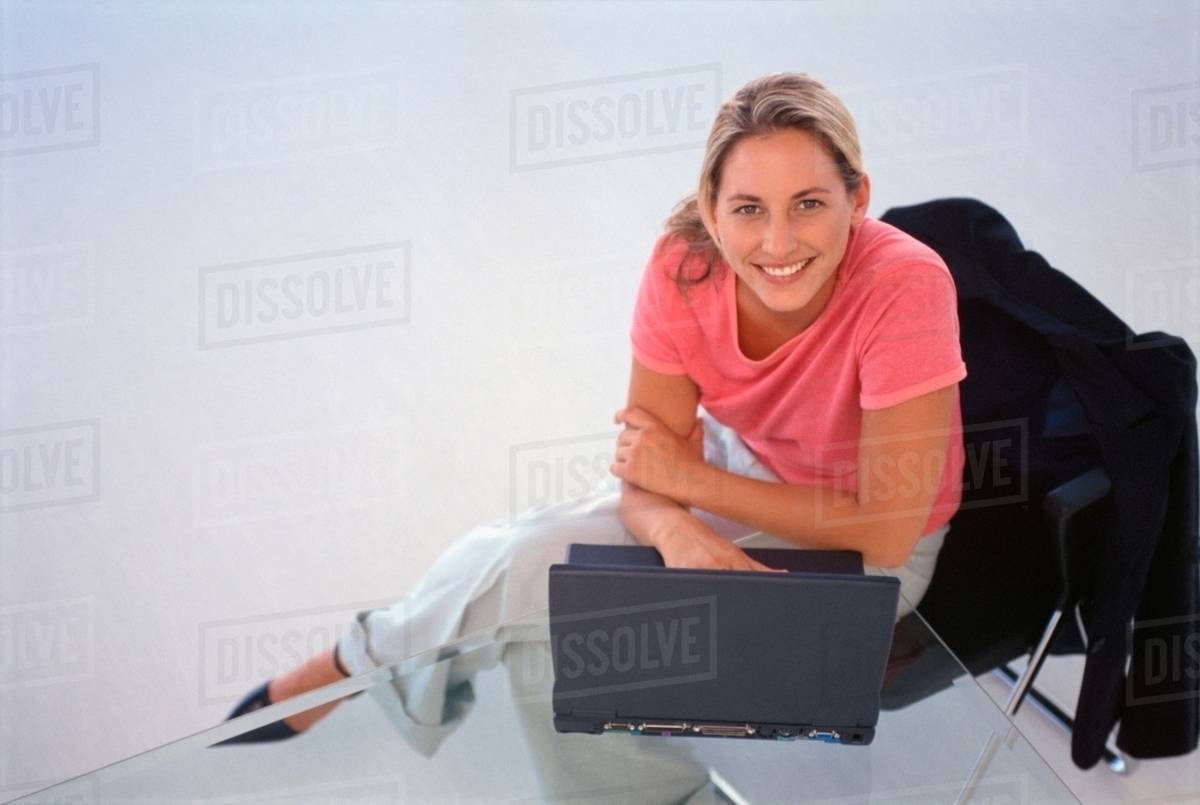 Businesswoman using laptop in office - Stock Photo - Dissolve
