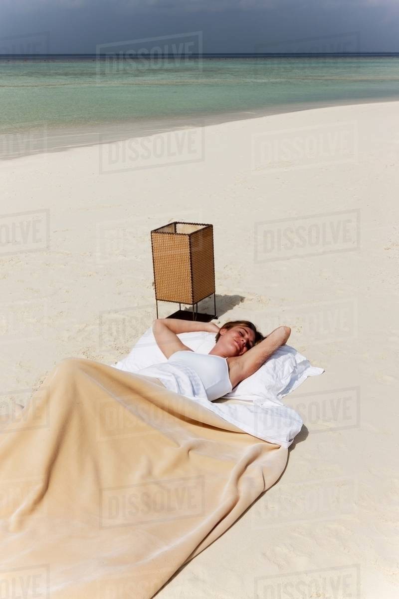 Woman sleeping in bed on beach - Stock Photo - Dissolve