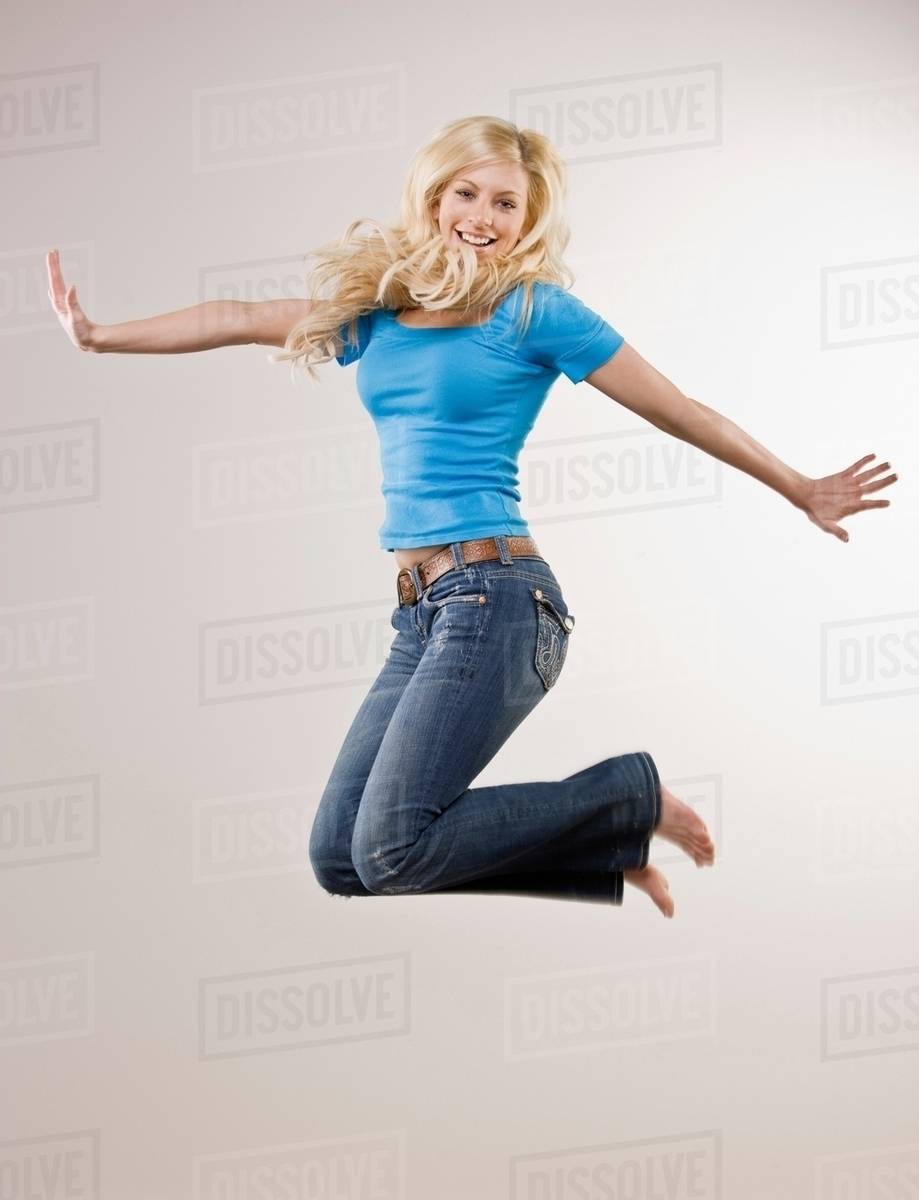 Smiling girl jumping in mid air - Royalty-free Stock Photo | Dissolve