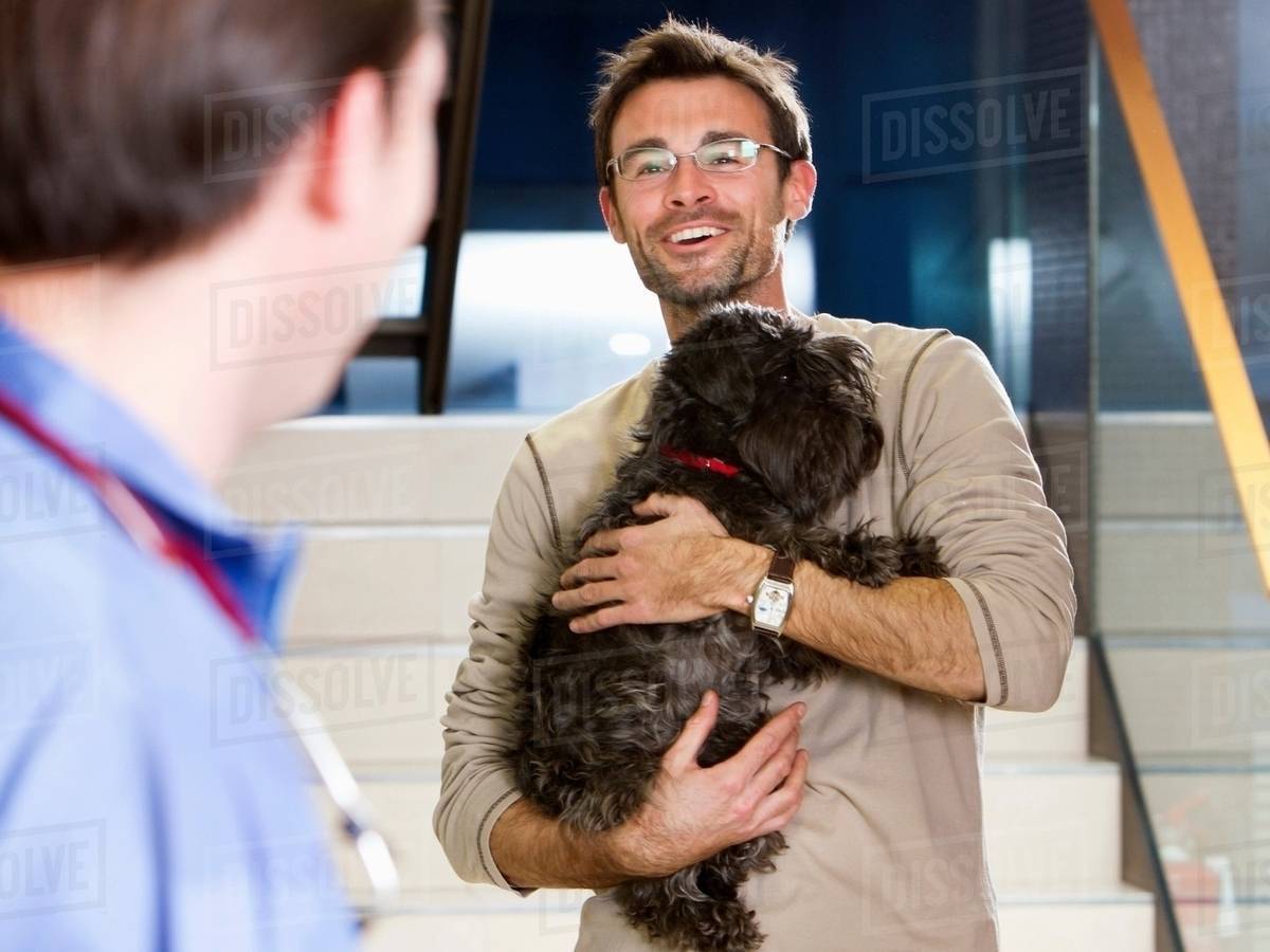 Man holding dog at vet - Royalty-free Stock Photo | Dissolve