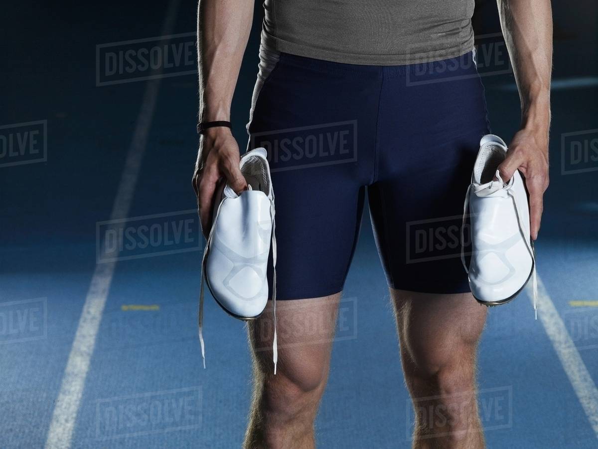 Man carrying running shoes on track - Stock Photo - Dissolve