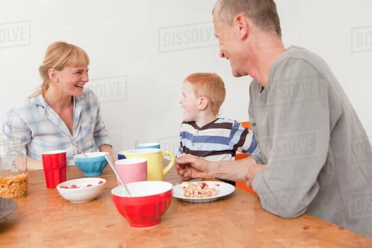 Family laughing at breakfast - Stock Photo - Dissolve