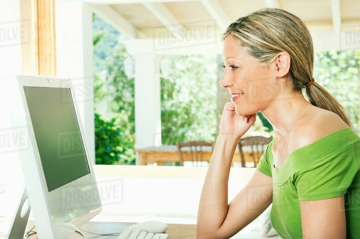 Woman using computer at desk - Stock Photo - Dissolve