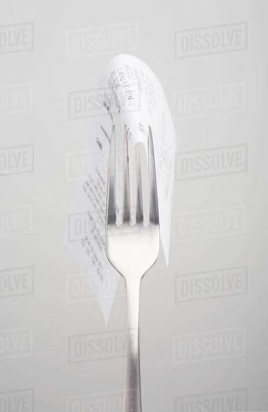 Close up of receipt on fork - Stock Photo - Dissolve