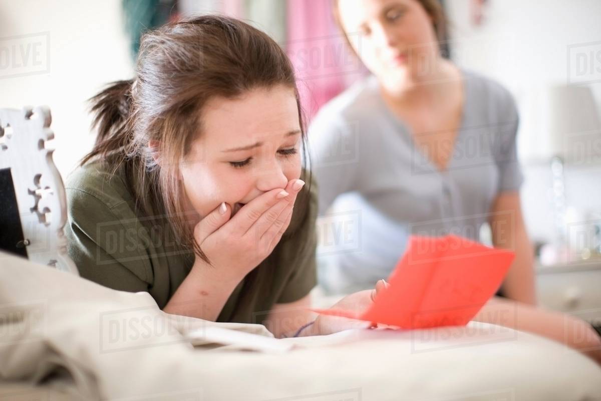 Crying teenage girl reading letter - Stock Photo - Dissolve