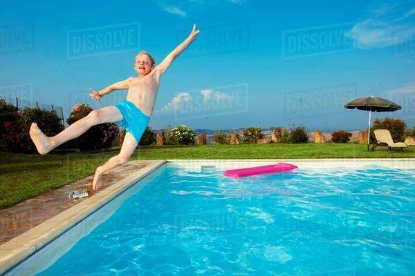 Boy jumping into swimming pool - Stock Photo - Dissolve