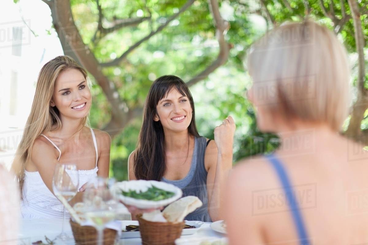 Women eating at table outdoors - Royalty-free Stock Photo | Dissolve