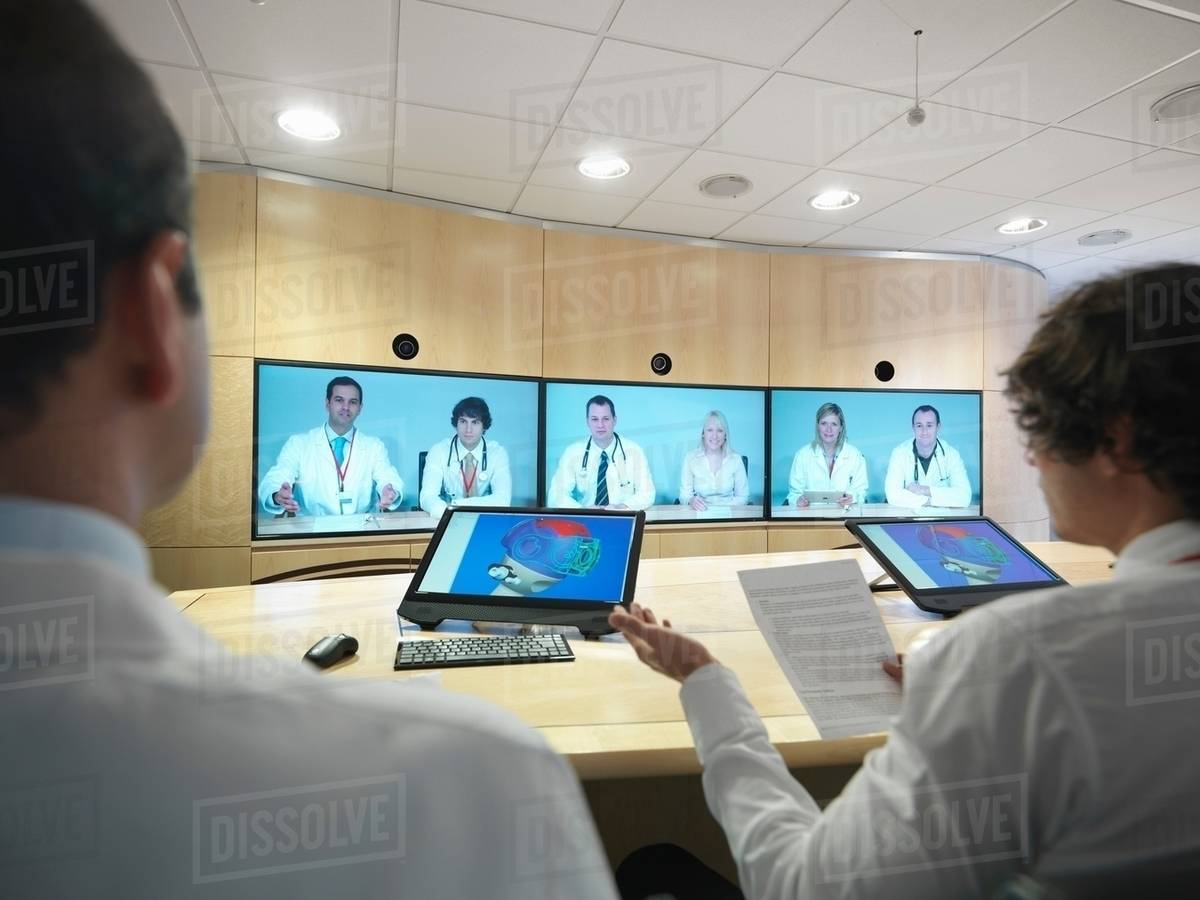 Medical professionals in meeting room using screens in video conference ...