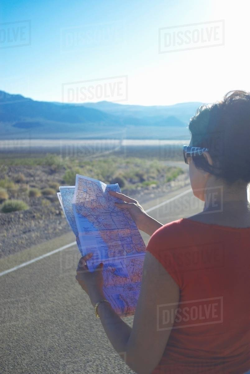 Woman reading map on rural road - Stock Photo - Dissolve
