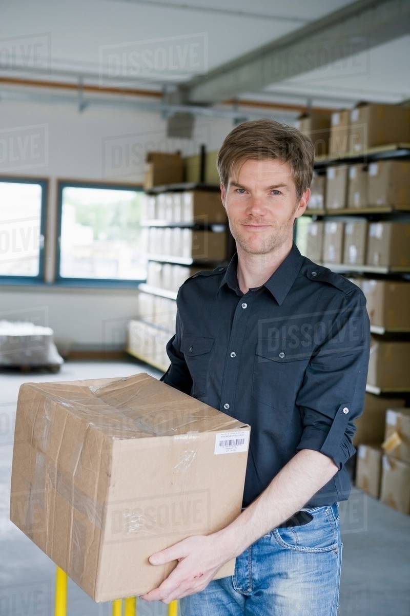 Man carrying cardboard boxes in storage - Stock Photo - Dissolve